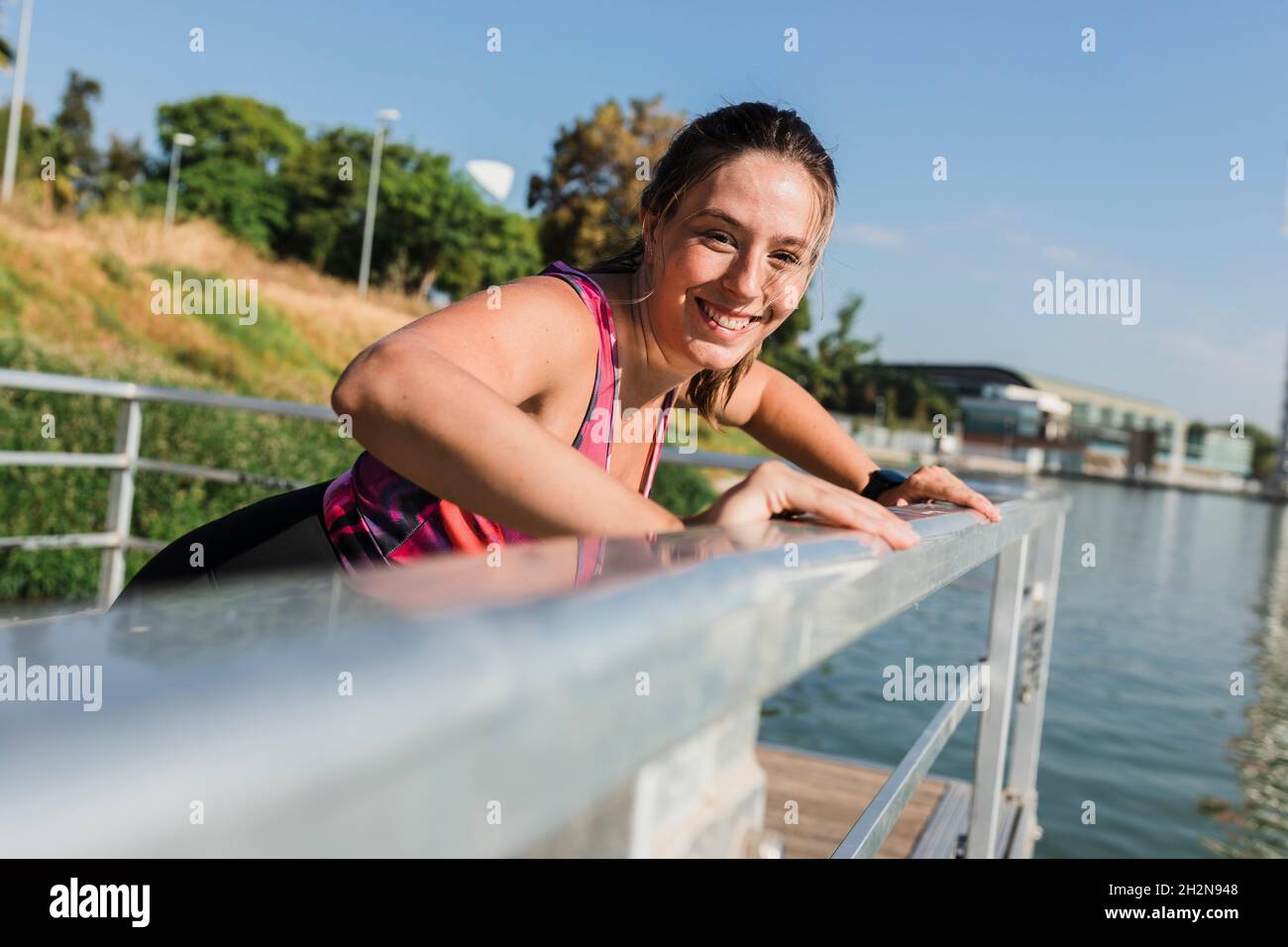 Beautiful female athlete practicing exercise at railing during sunny ...