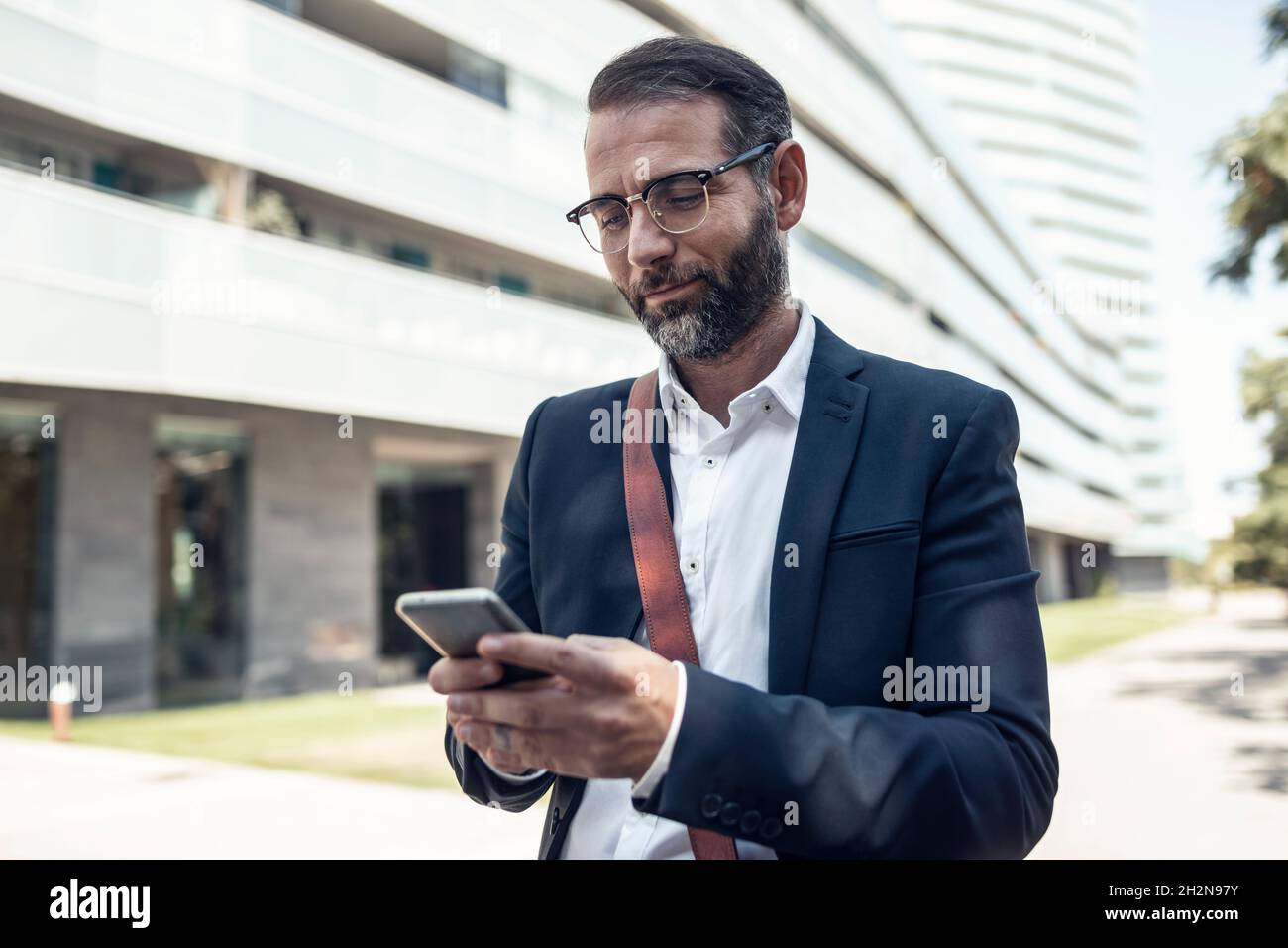 Businessman with eyeglasses using smart phone Stock Photo - Alamy