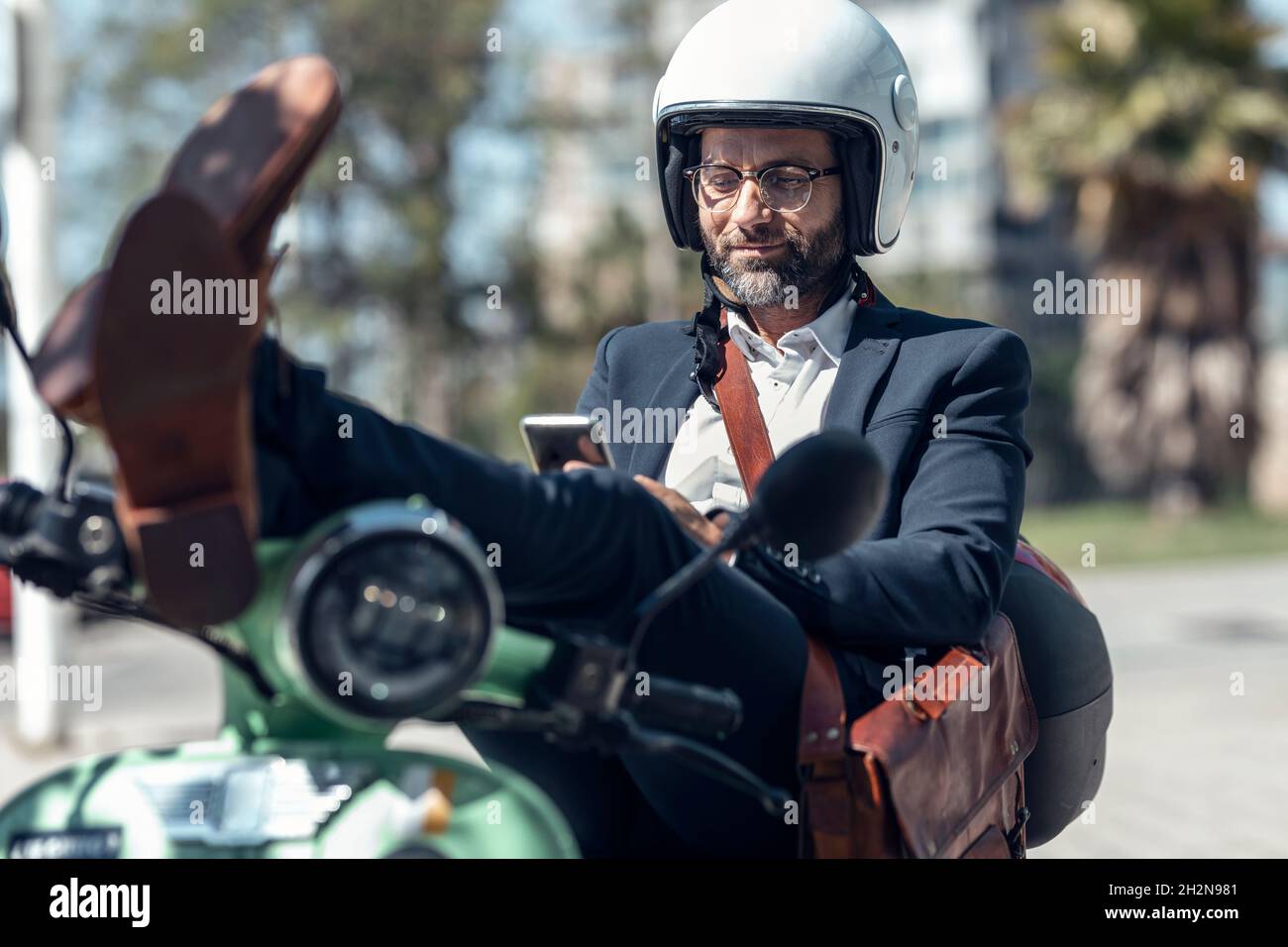Male professional using mobile phone while sitting with feet up on ...
