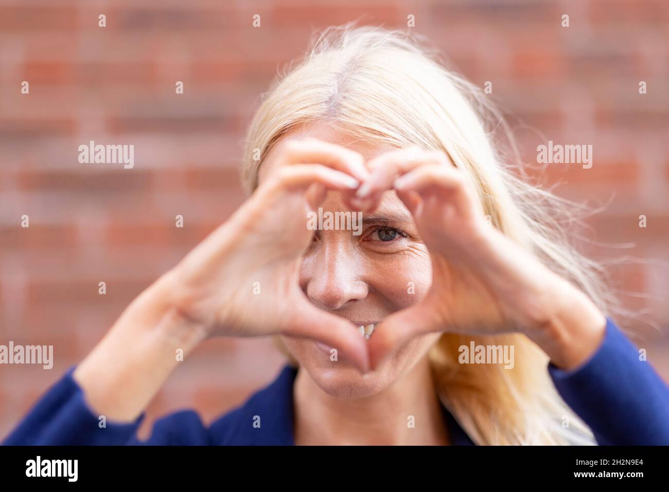 Mature woman making heart symbol with hands Stock Photo - Alamy