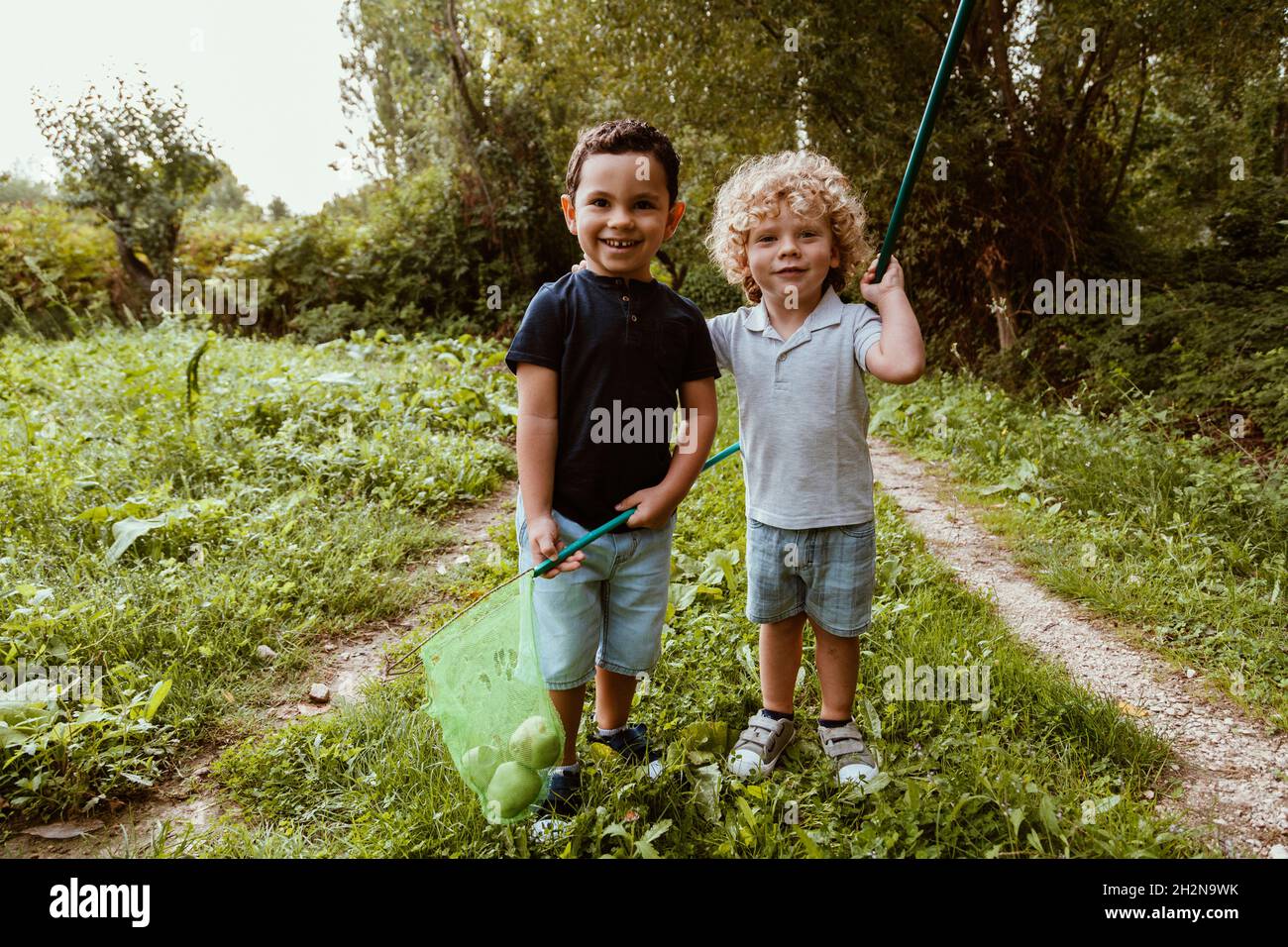 Cute boys standing on grass holding pears in fishing net Stock Photo ...