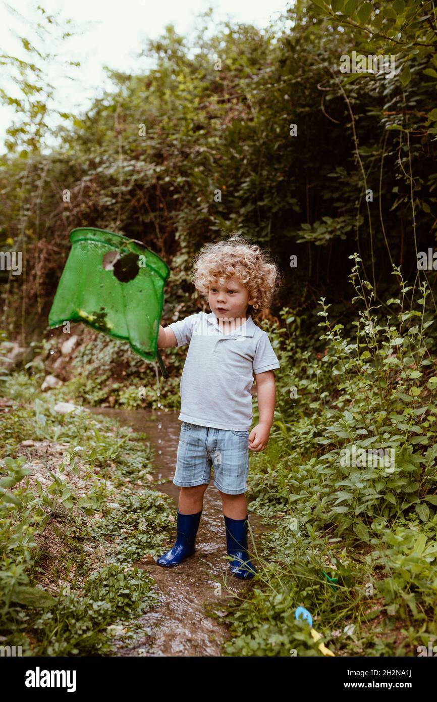 Boy holding fishing net with garbage while standing in forest Stock ...