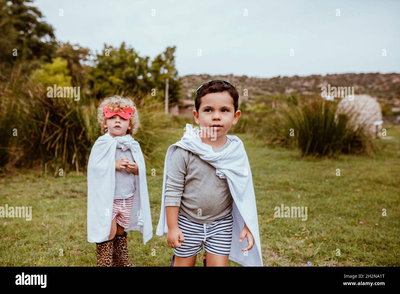 Boys wearing capes standing on meadow Stock Photo - Alamy
