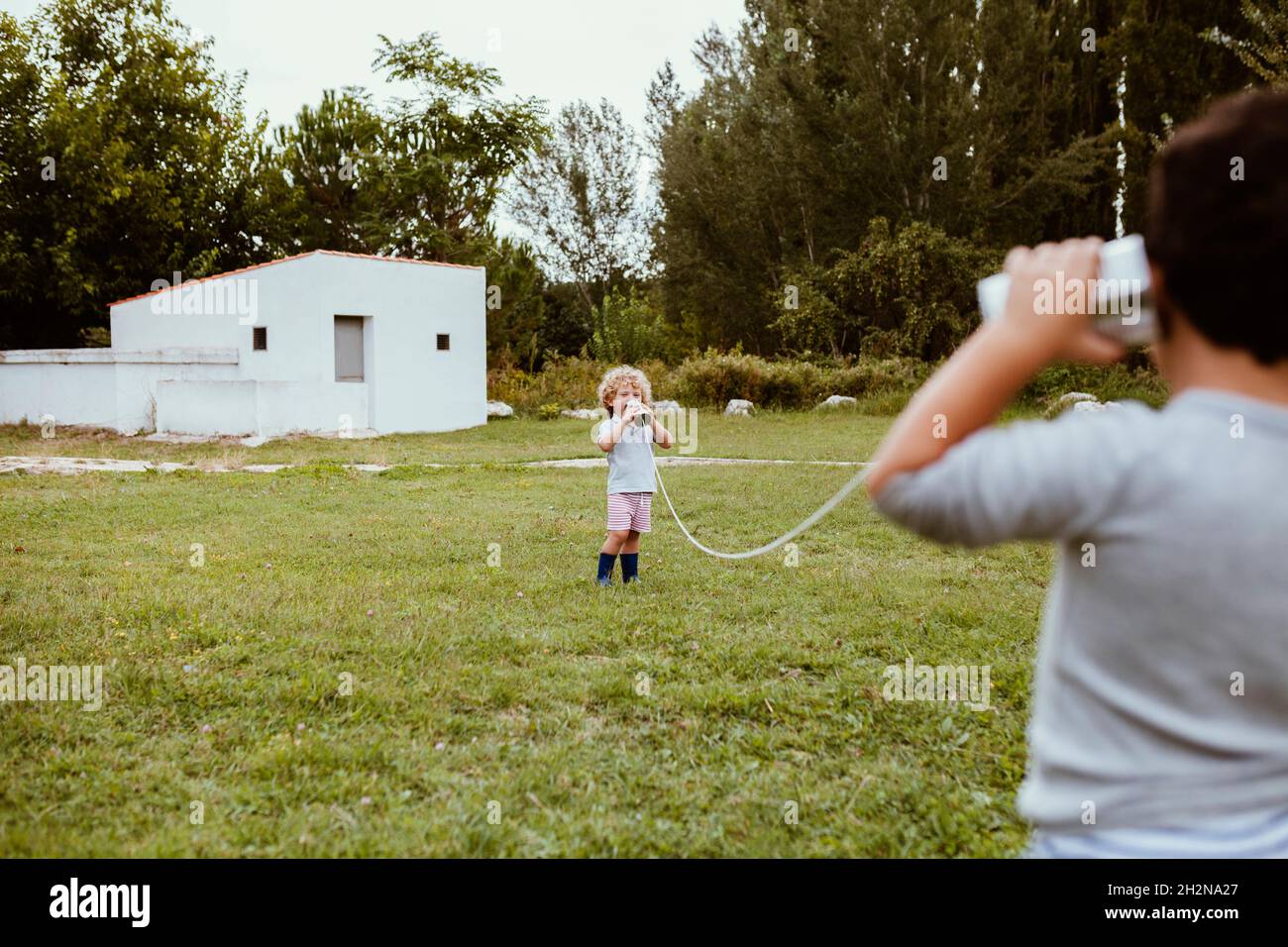 Boy talking through tin can phone while playing with male friend on ...