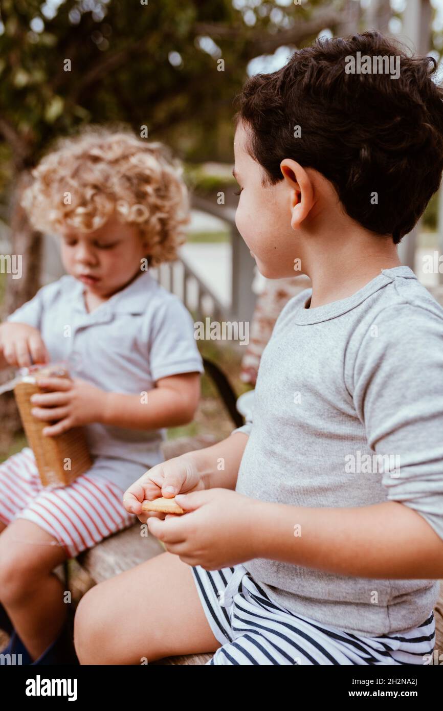 Boys eating biscuits while sitting on bench Stock Photo - Alamy