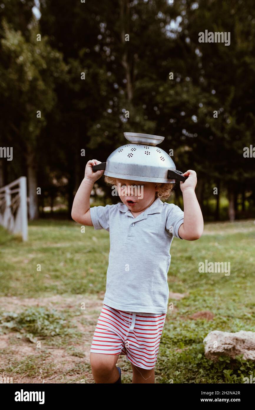 Boy wearing colander on head while playing on meadow Stock Photo - Alamy