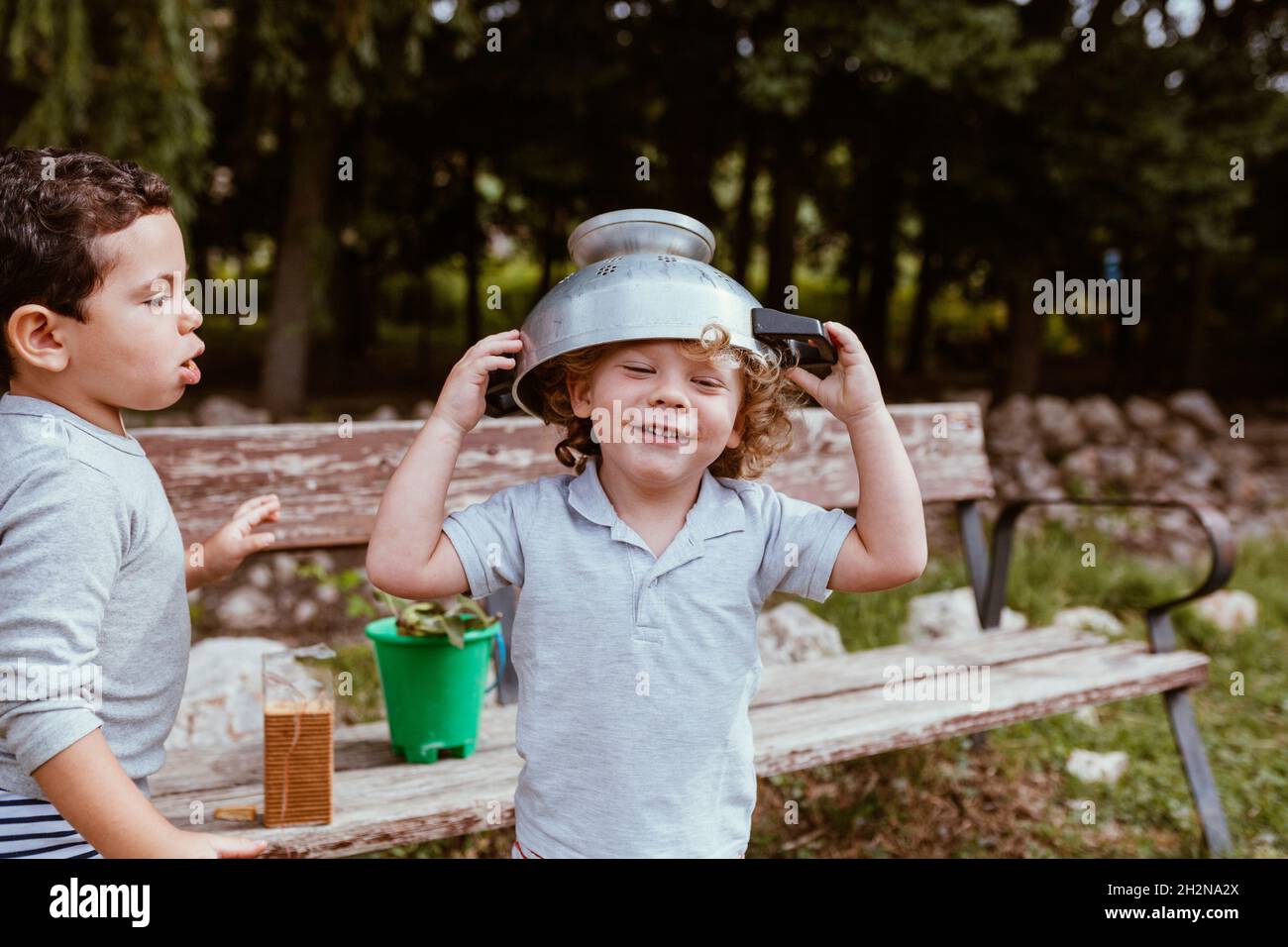 Happy boy wearing colander on head while standing by male friend Stock ...