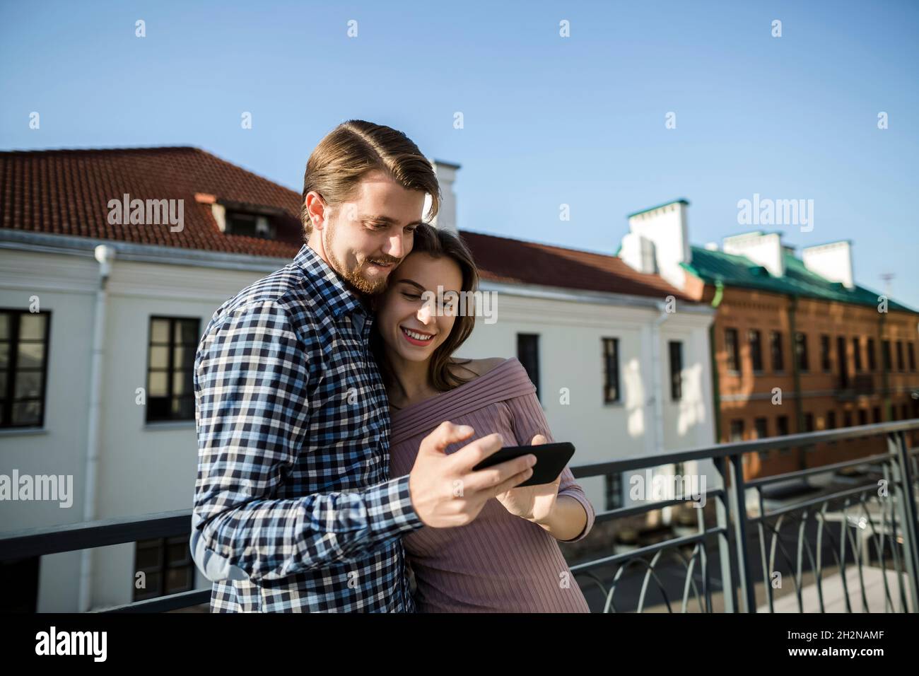 Young couple sharing mobile phone at rooftop Stock Photo - Alamy