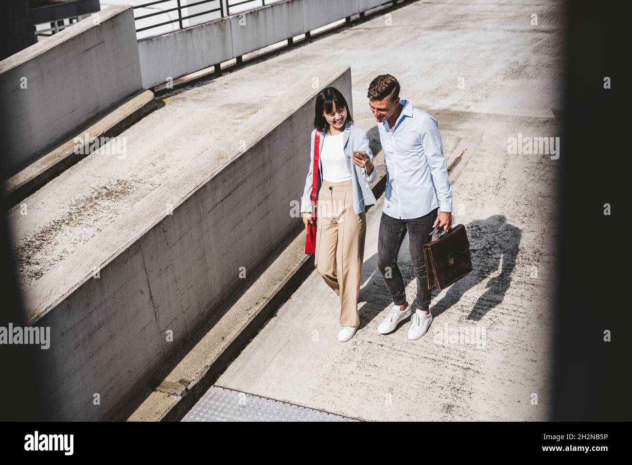 Male and female business professionals sharing mobile phone while ...