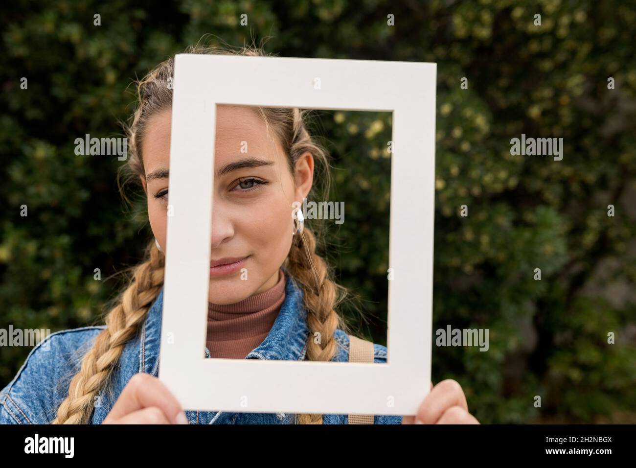 Young woman looking through white frame Stock Photo - Alamy