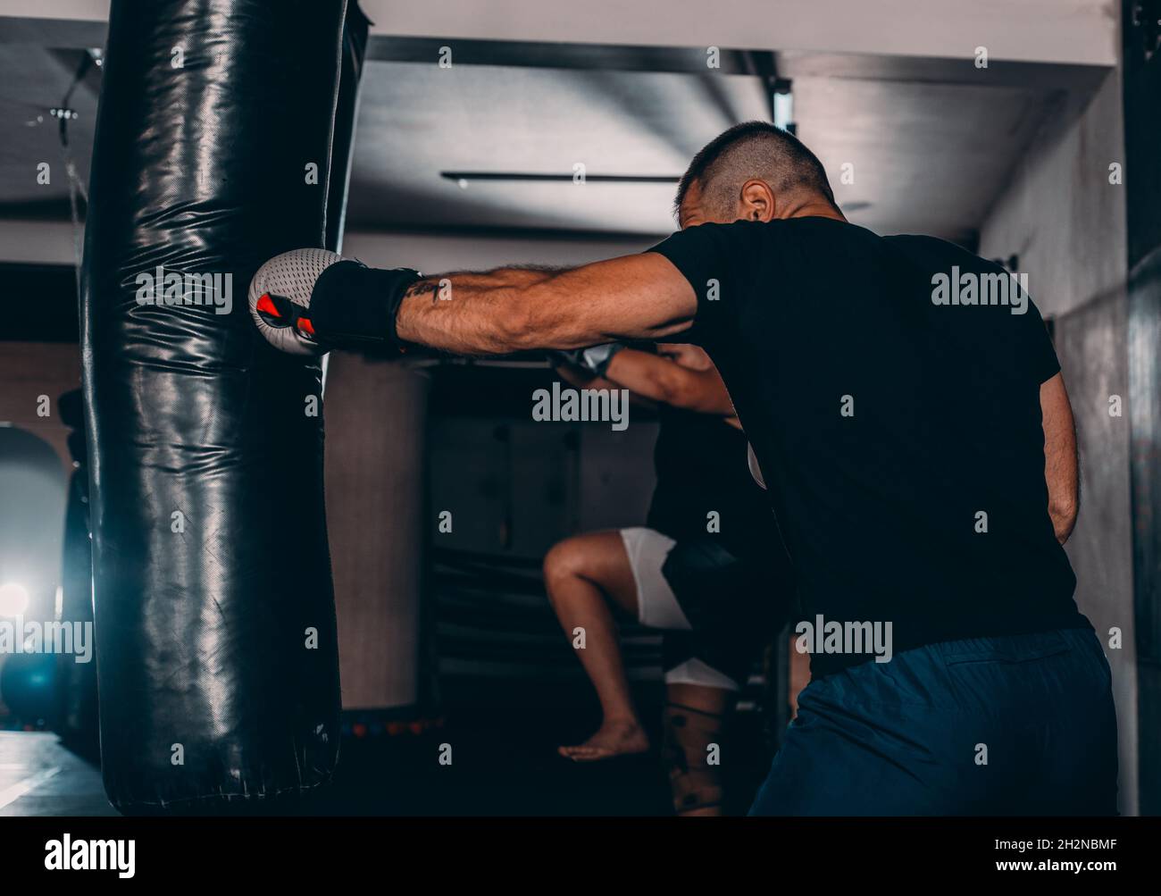 Muscular handsome fighter giving a forceful forward kick during a ...