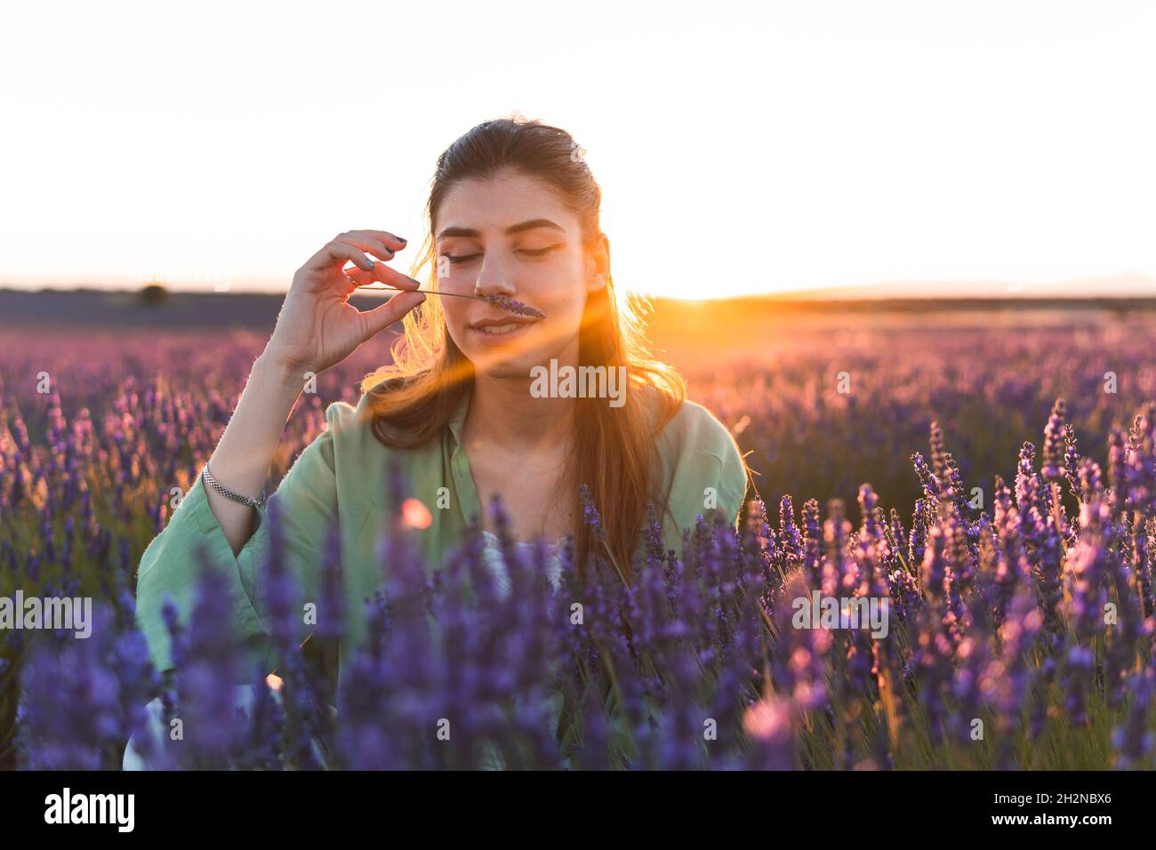 Woman with brown hair crouching by plants on field Stock Photo - Alamy
