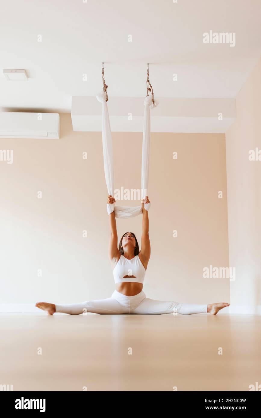 Sportswoman with legs splits practicing aerial yoga at studio Stock ...