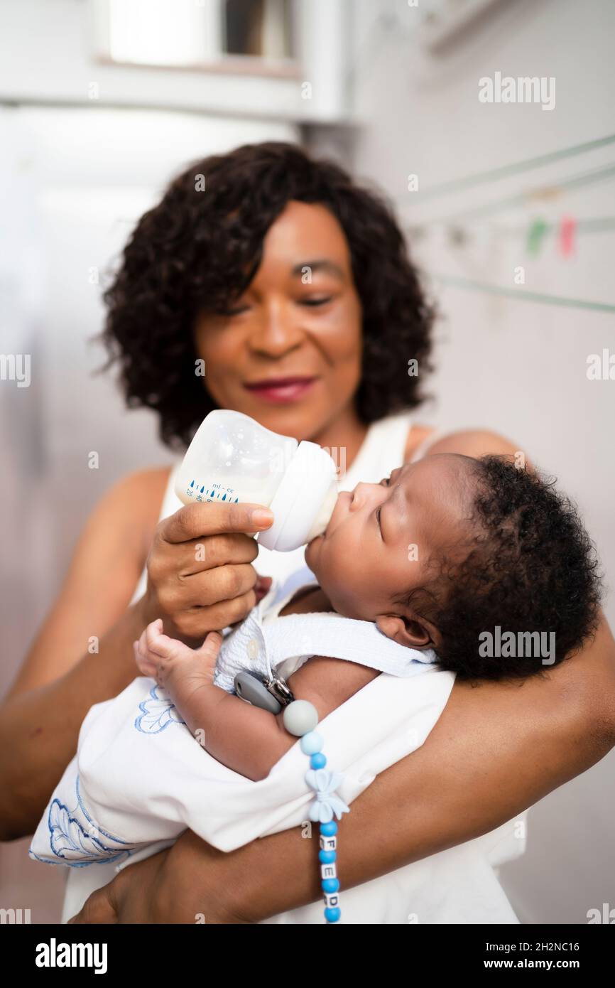 Mature woman feeding baby boy at home Stock Photo - Alamy
