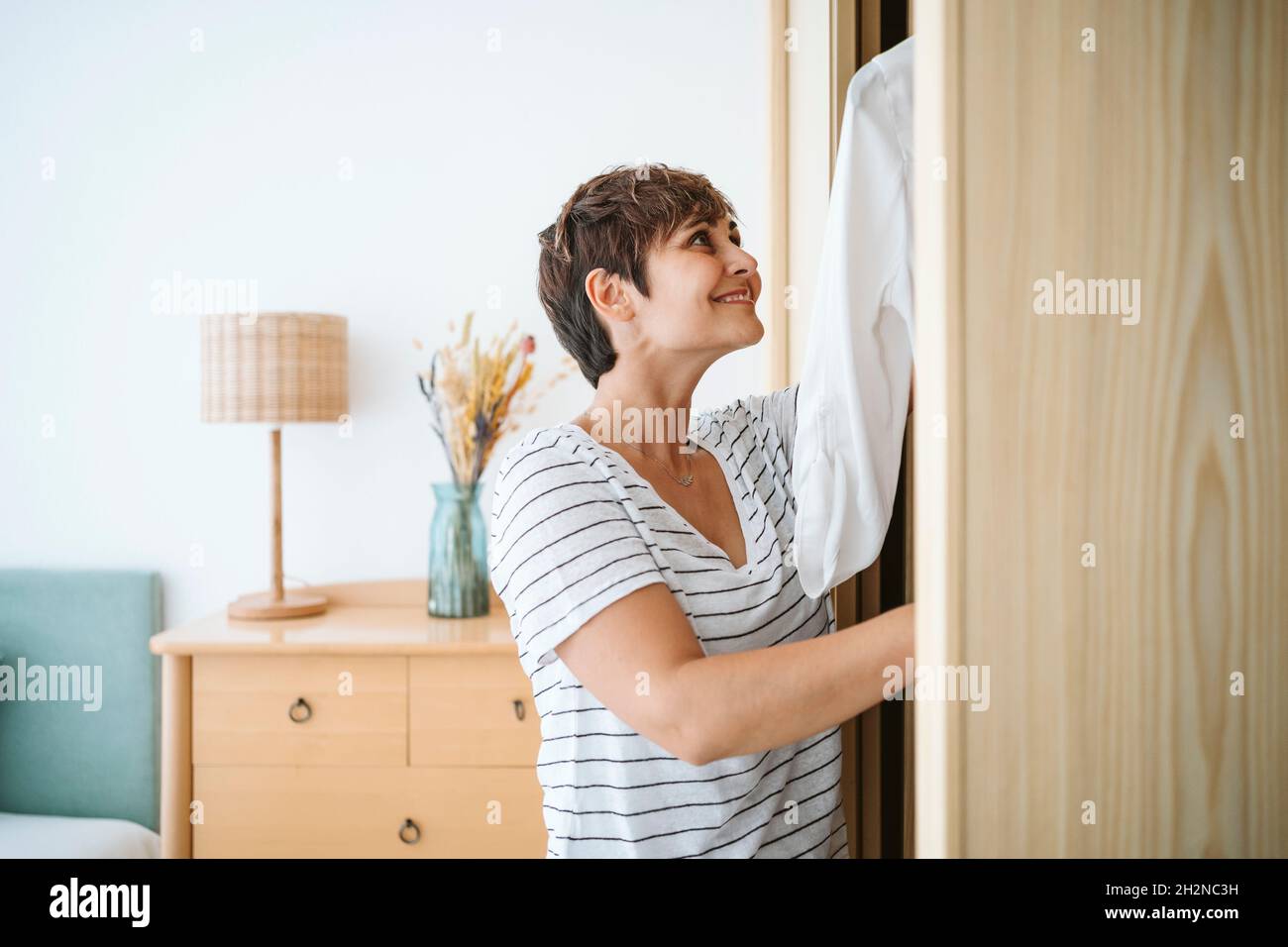 Smiling woman searching for clothes in closet Stock Photo - Alamy