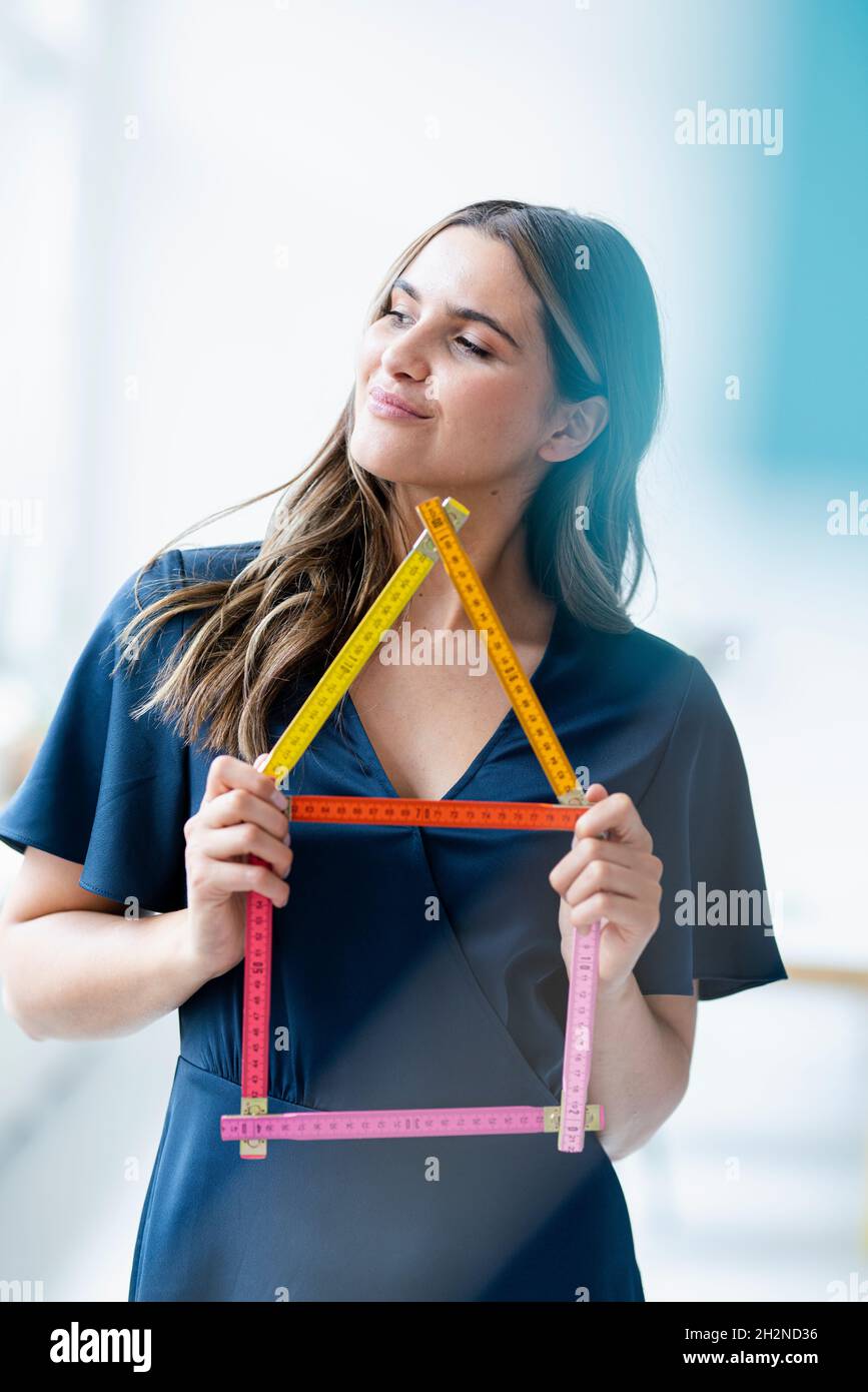 Female architect holding house shape ruler in office Stock Photo - Alamy