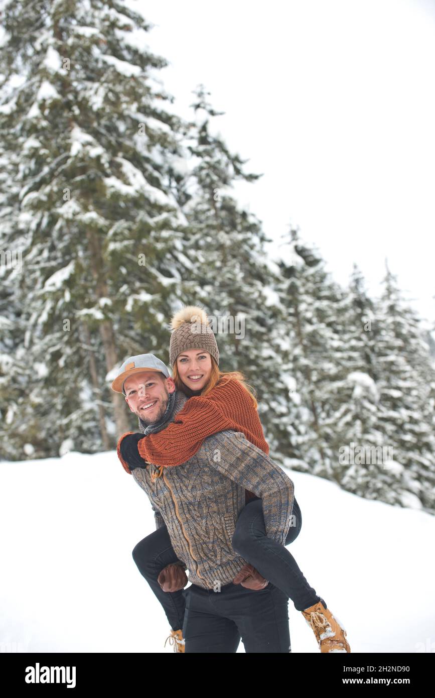Man giving piggyback ride to woman on snow during winter Stock Photo ...