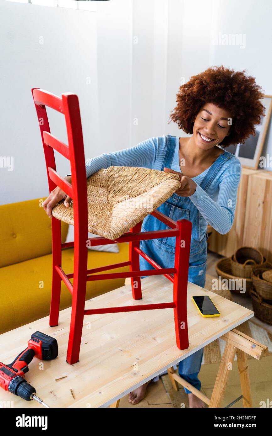 Redhead woman repairing chair with electric screwdriver at home Stock ...