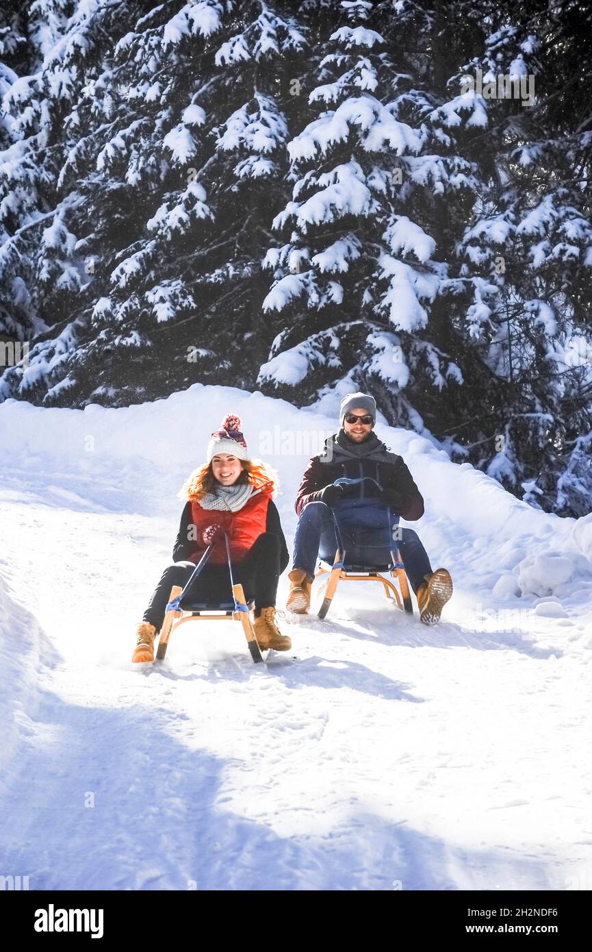 Couple sledding on snow during sunny day in winter Stock Photo - Alamy