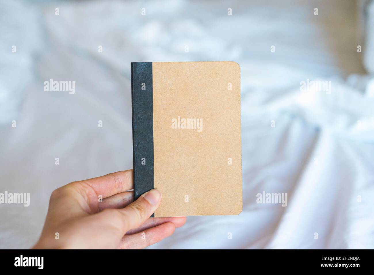 Man holding book over bed at home Stock Photo - Alamy