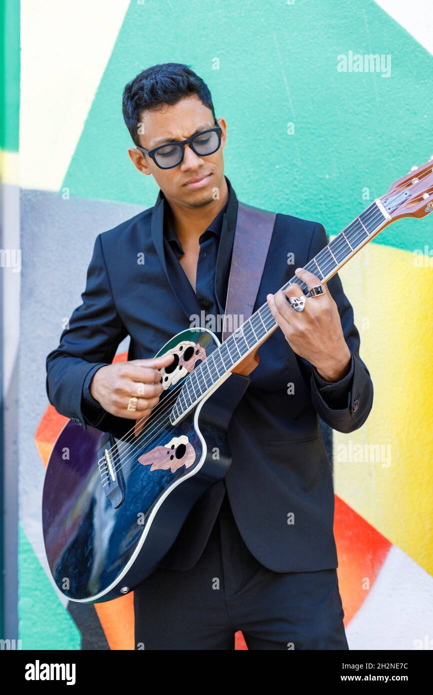 Male musician wearing eyeglasses playing guitar Stock Photo - Alamy