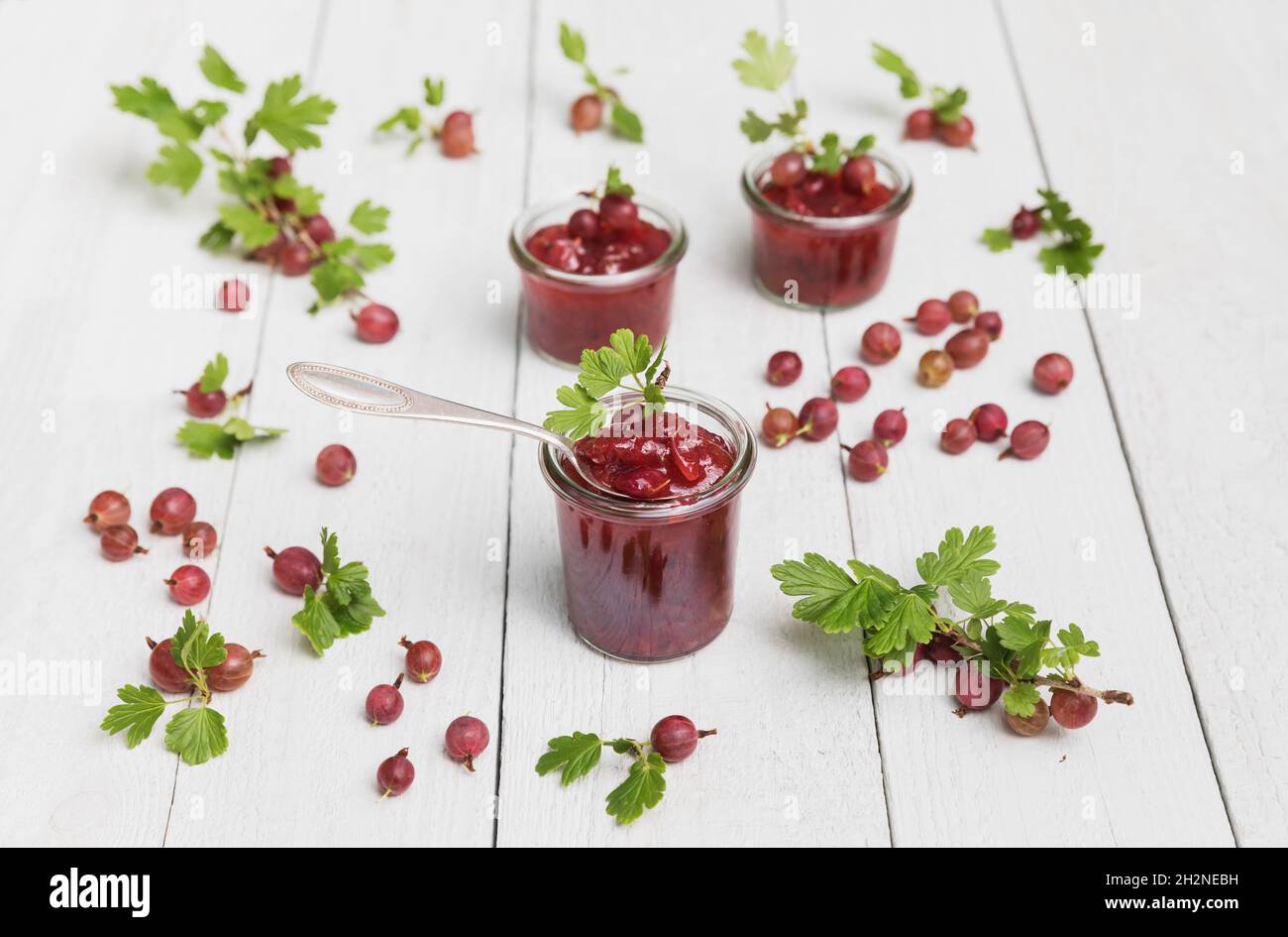 Raw gooseberries (Ribes uva-crispa) and jars of homemade gooseberry jam ...