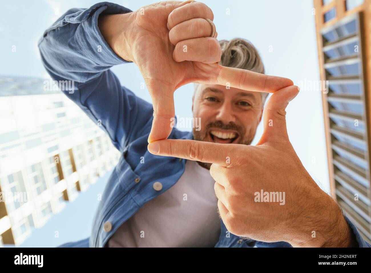 Man winking while looking through finger frame Stock Photo - Alamy