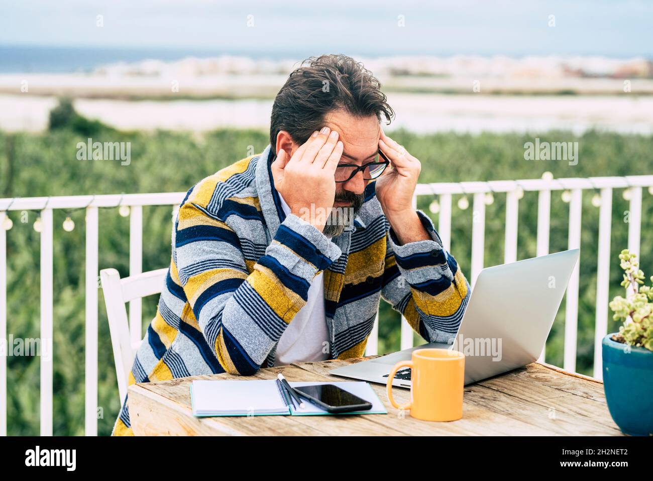 Man with head in hands sitting at table on rooftop Stock Photo - Alamy