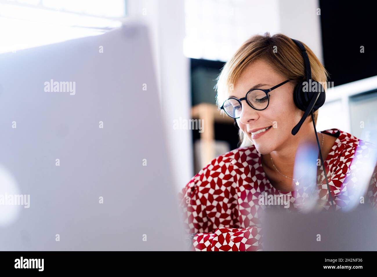 Female customer service representative working on laptop in office ...