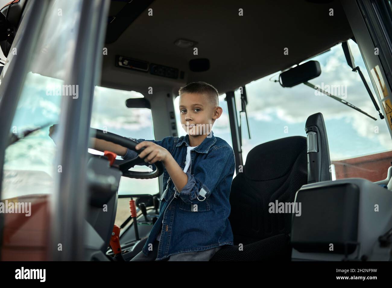 Boy driving tractor in agricultural field Stock Photo - Alamy