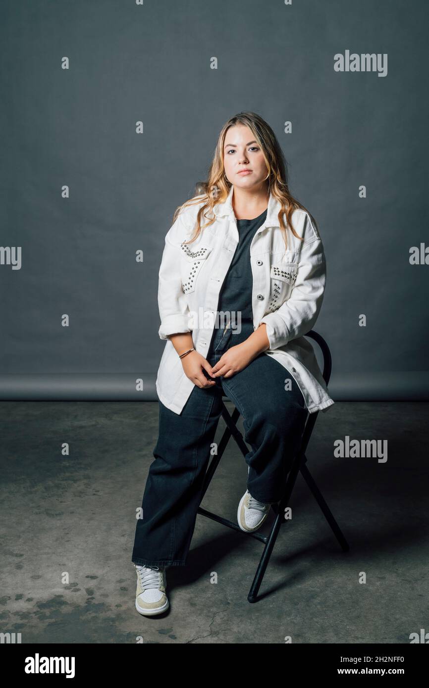 Overweight confident young woman sitting on chair in studio Stock Photo ...
