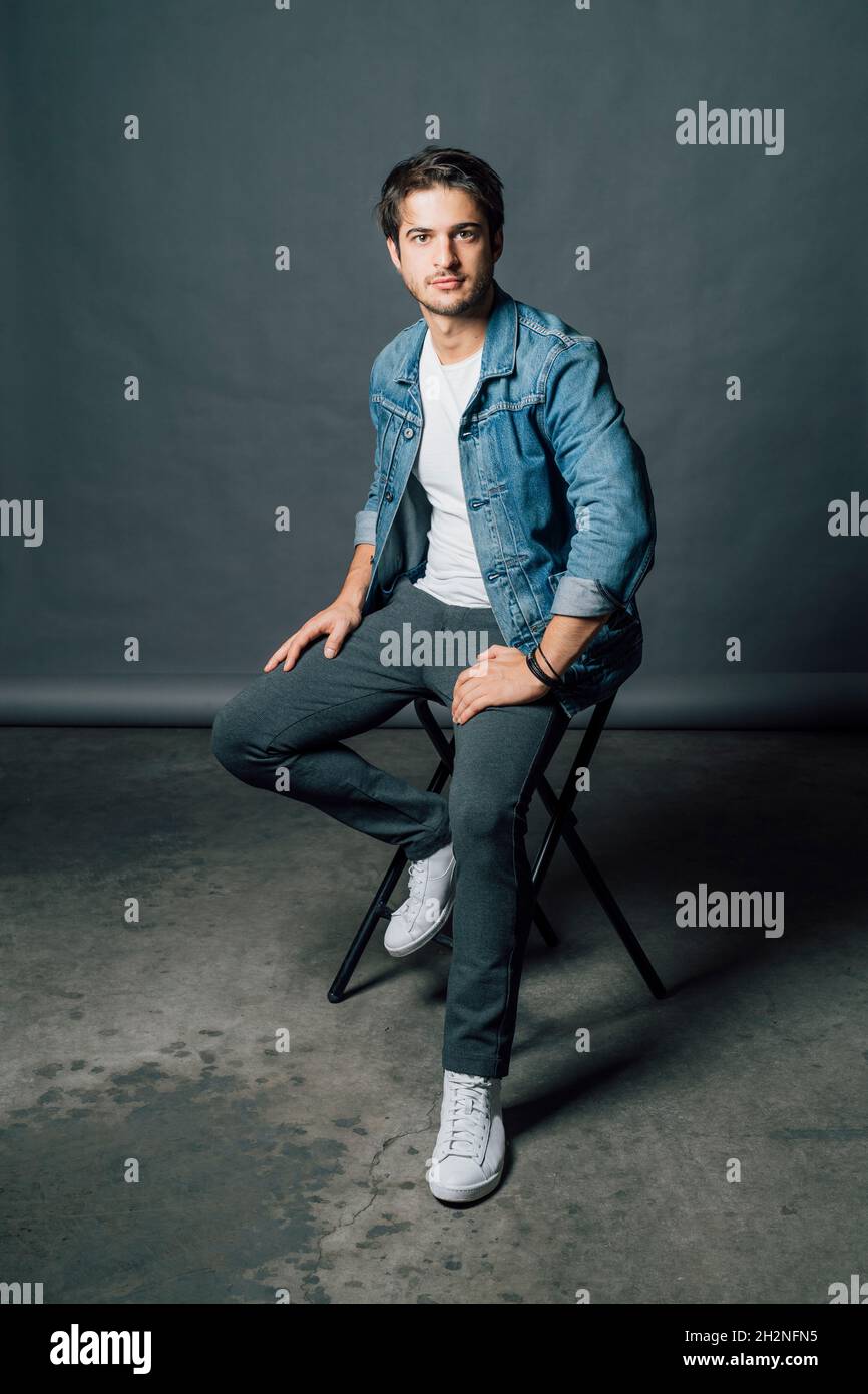 Confident man sitting on chair in studio Stock Photo - Alamy