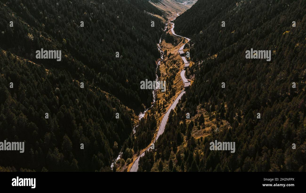 Aerial view of winding road stretching along river in autumn valley ...