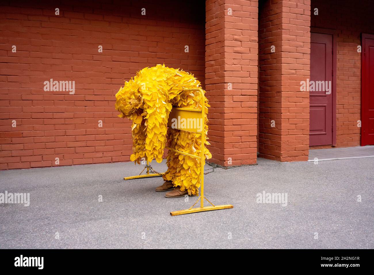 Woman in leaf costume leaning on barricade Stock Photo - Alamy