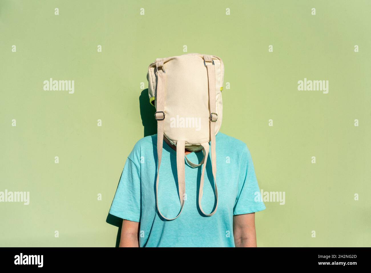 Woman with backpack on face standing in front of green wall Stock Photo ...