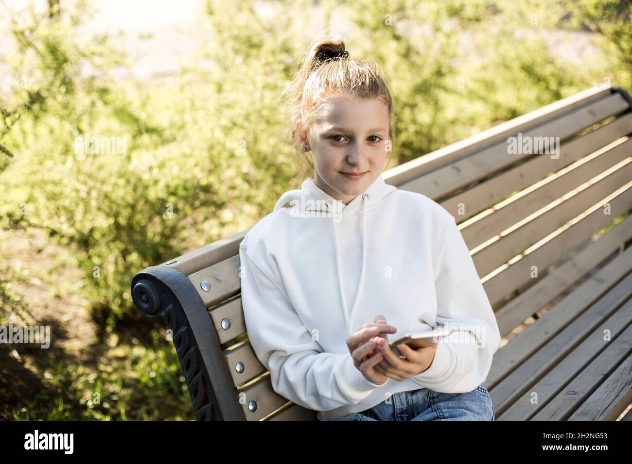 Girl with smart phone sitting on bench Stock Photo - Alamy