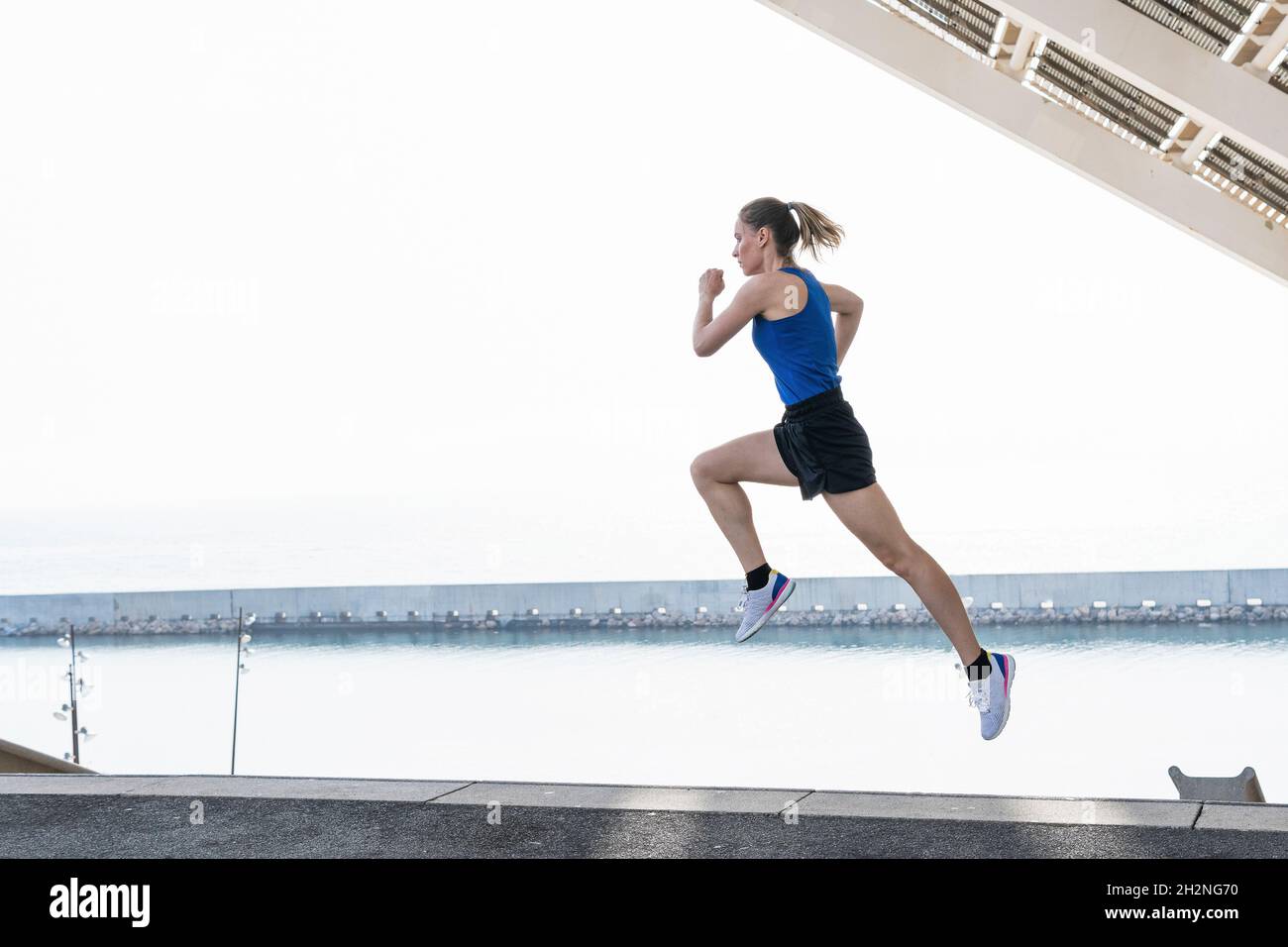 Female athlete jumping while exercising on road Stock Photo - Alamy