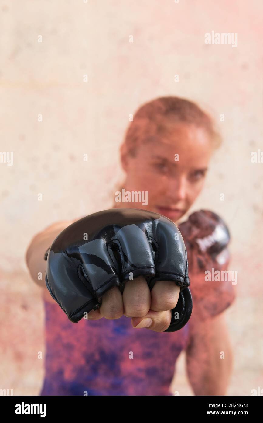 Female athlete punching while wearing glove in front of wall Stock ...