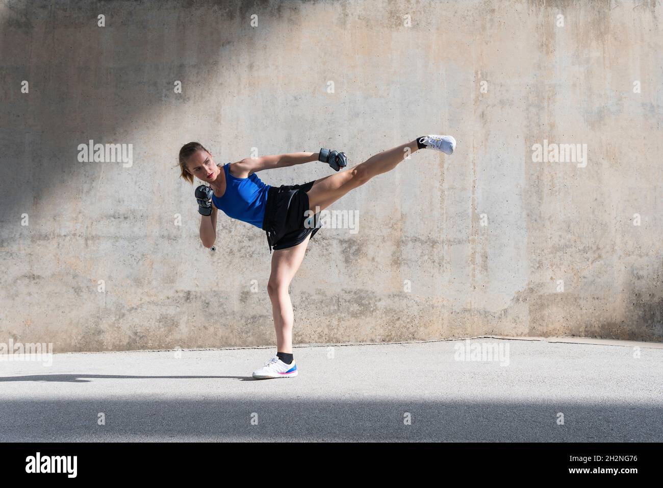 Female athlete practicing kicks in front of wall Stock Photo - Alamy