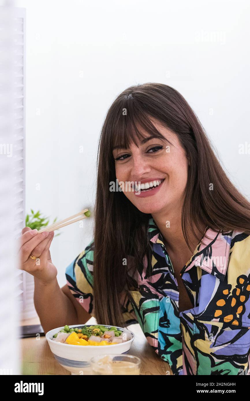 Happy woman eating poke with chopsticks at restaurant Stock Photo - Alamy