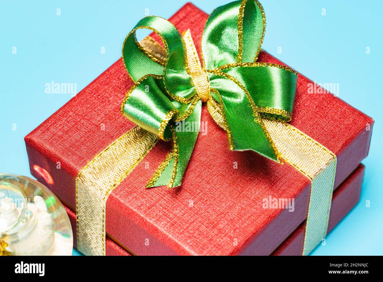 Red gift boxes with green ribbon lay on the table, cyan background ...