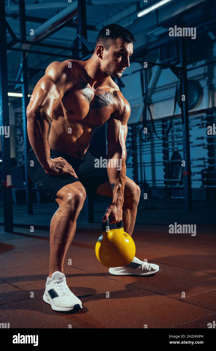 One muscled athlete, bodybuilder workouts alone at sport gym, indoors ...