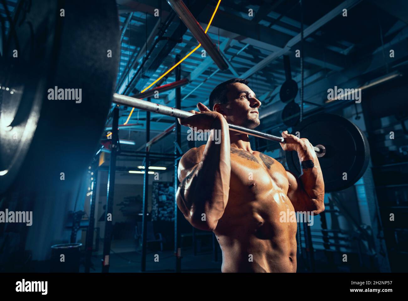 Close-up young man, muscled athlete, bodybuilder training alone at ...
