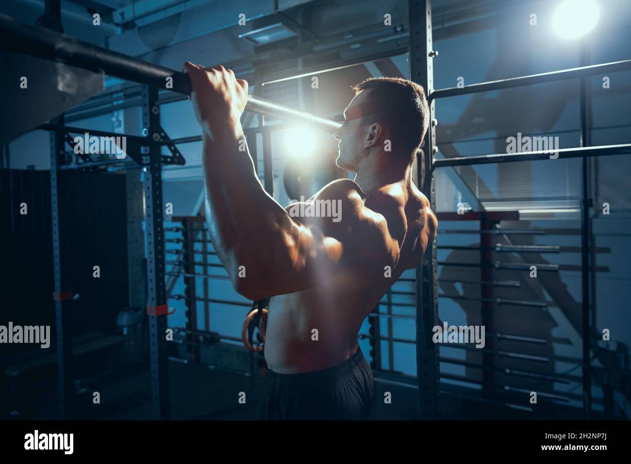 Portrait of muscled athlete, bodybuilder workouts alone at sport gym ...