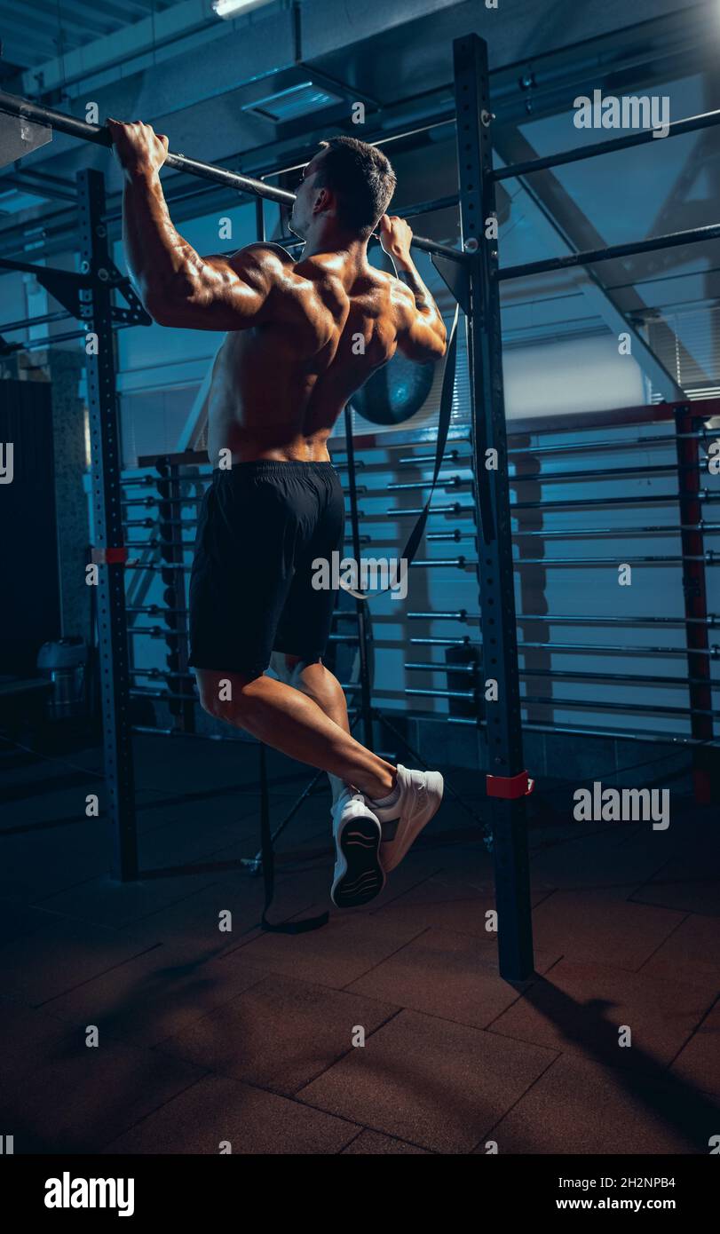 Portrait of muscled athlete, bodybuilder workouts alone at sport gym ...