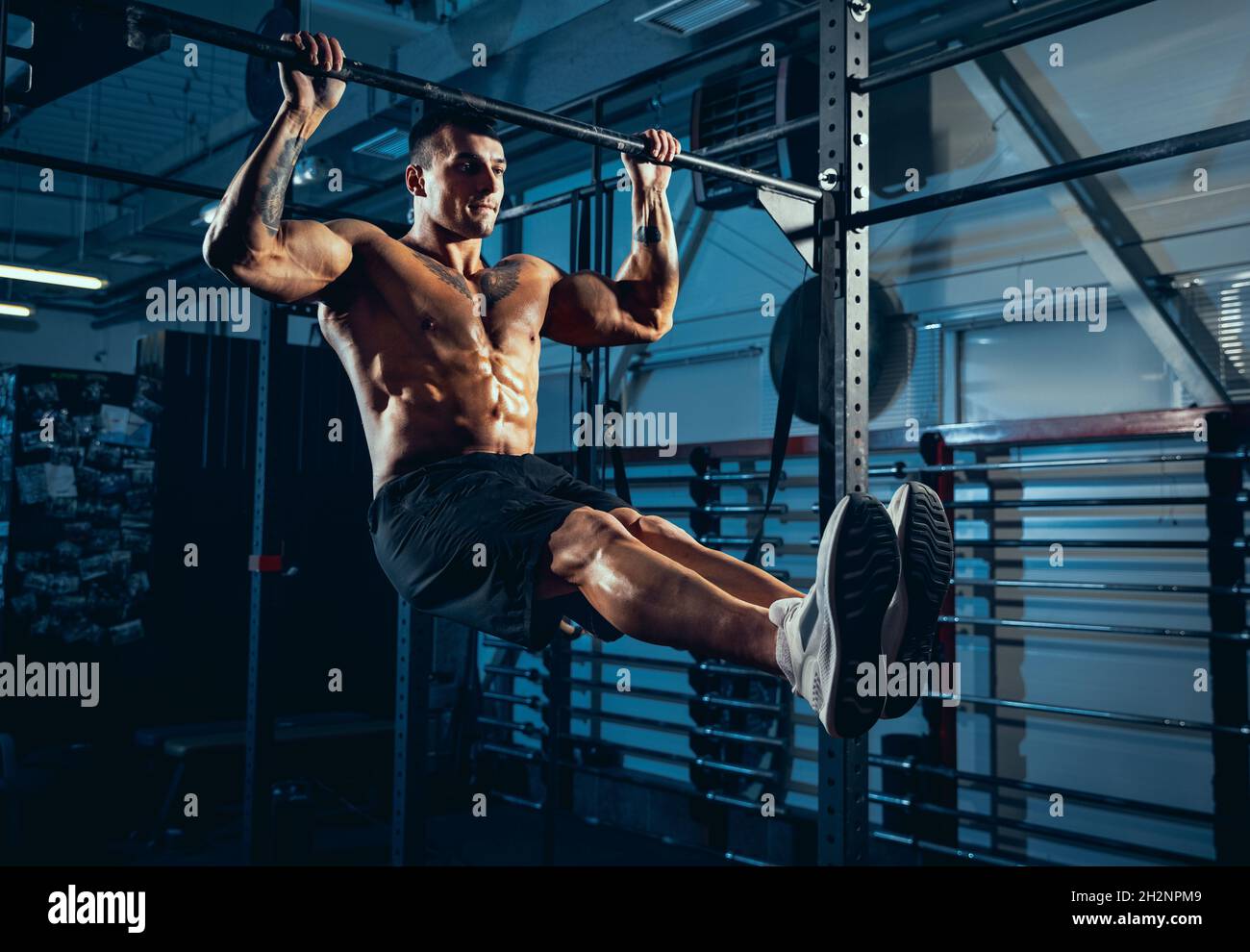 Portrait of muscled athlete, bodybuilder workouts alone at sport gym ...