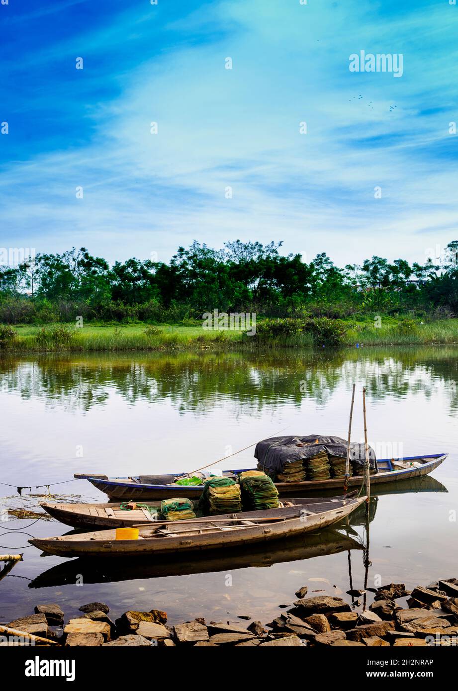 Three boats moored next to each other on a channel on the Thu Bon River ...