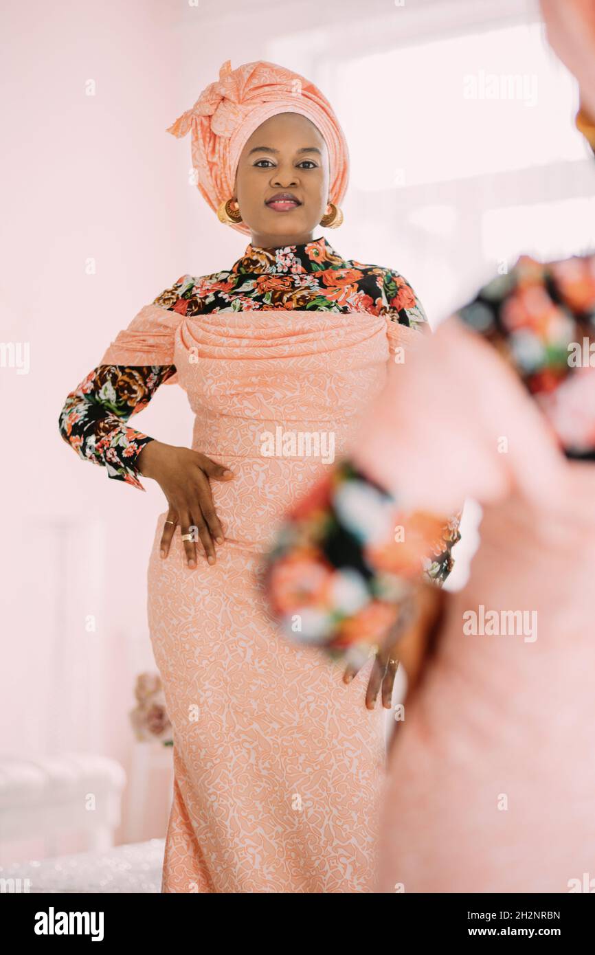 Playful charming African lady in elegant trendy pink dress with ethnic ...