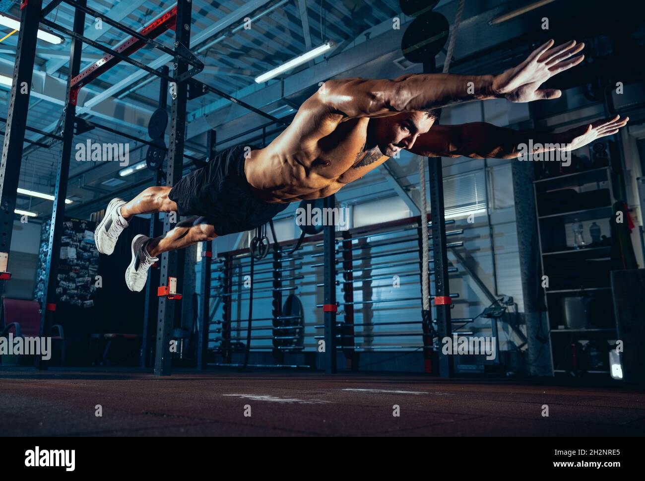 Portrait of muscled athlete, bodybuilder workouts alone at sport gym ...