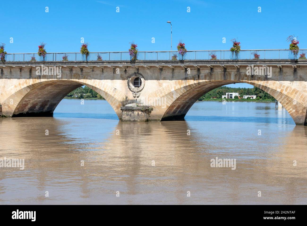 The arches of the stone bridge crossing the Dordogne river in Libourne ...